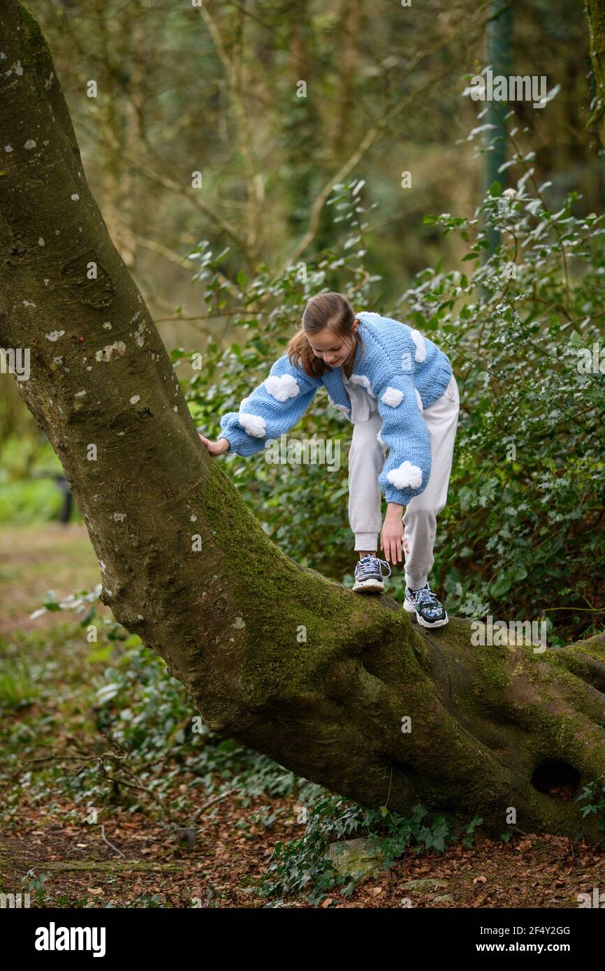 Young Girl crouching on a Tree Trunk Stock Photo - Alamy