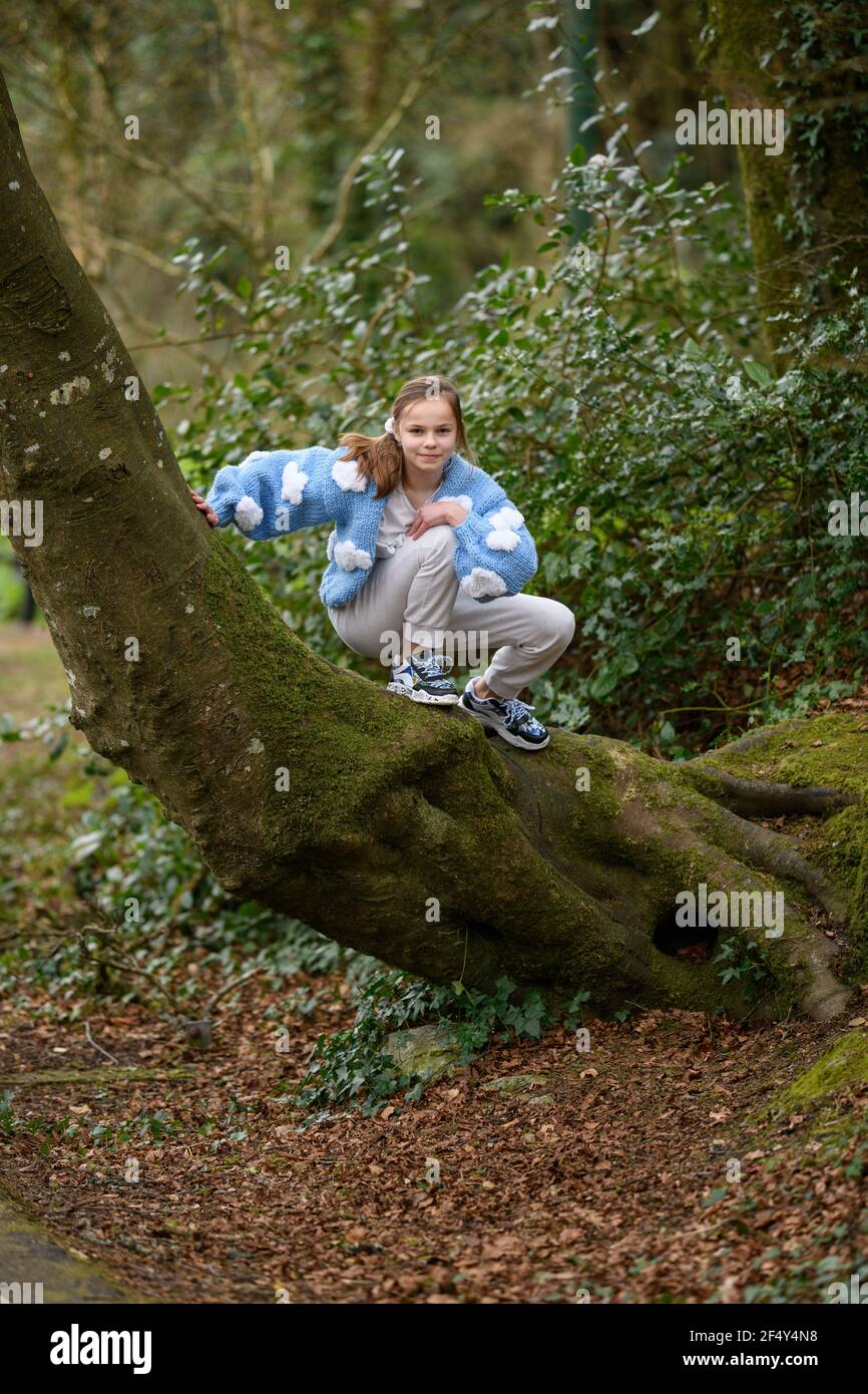 Young Girl crouching on a Tree Trunk Stock Photo - Alamy