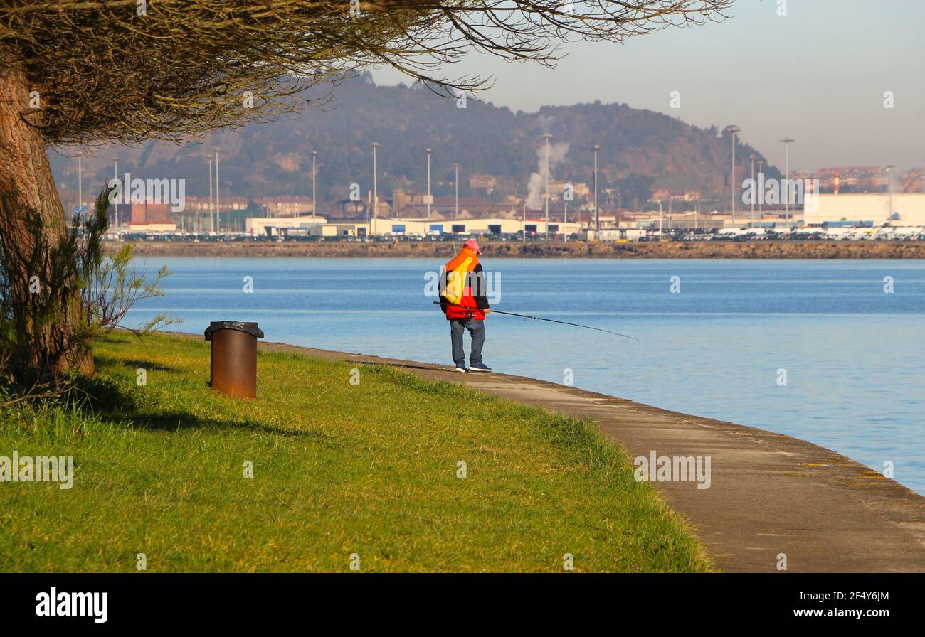 Lone man wearing brightly coloured clothes rod and line fishing from ...
