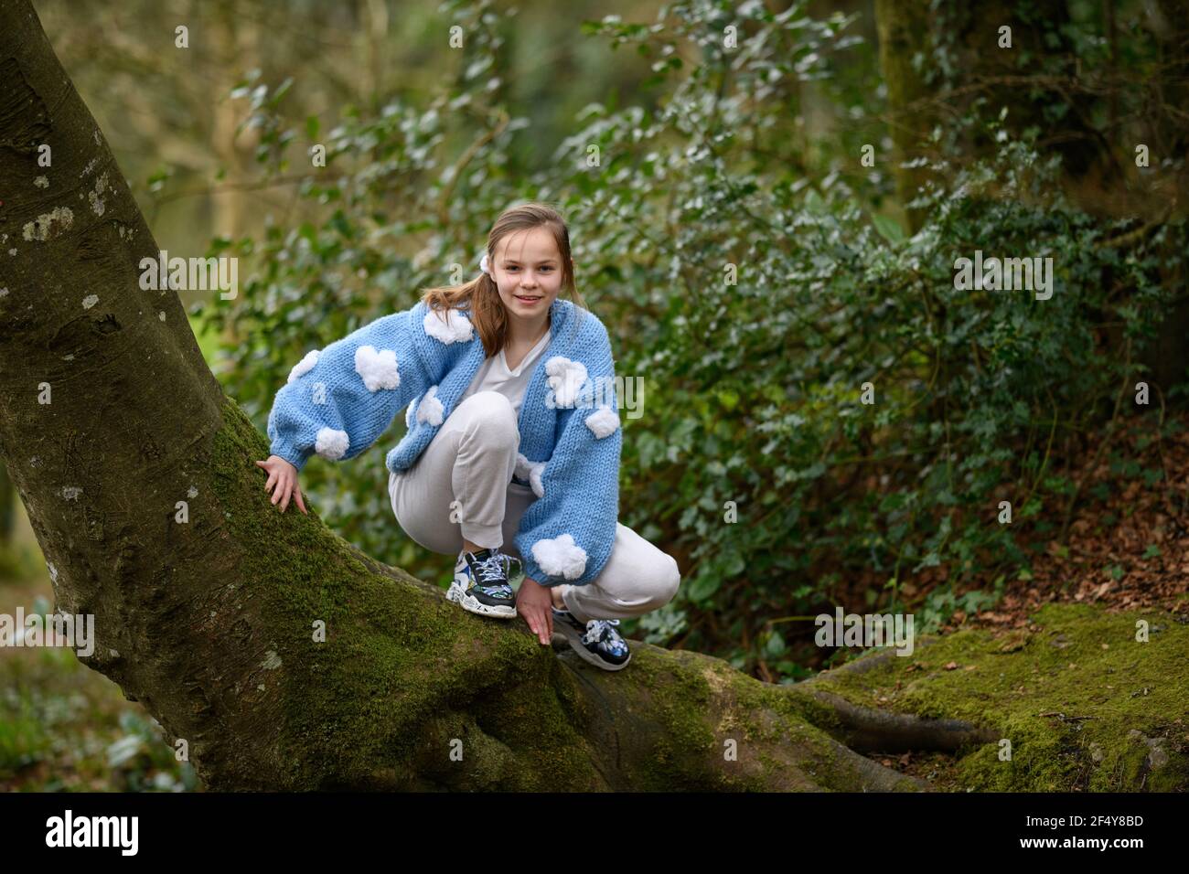Young Girl crouching on a Tree Trunk Stock Photo - Alamy