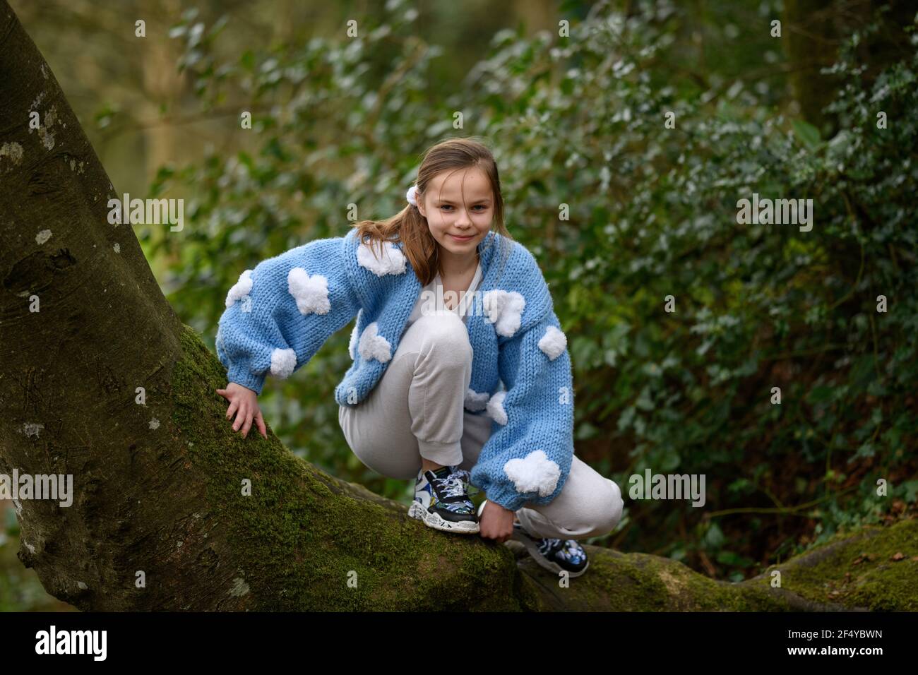 Young Girl crouching on a Tree Trunk Stock Photo - Alamy