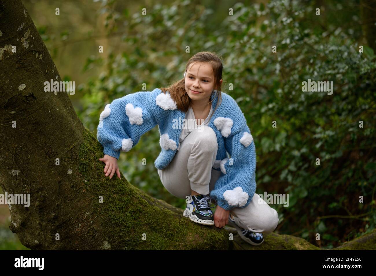 Young Girl crouching on a Tree Trunk Stock Photo - Alamy