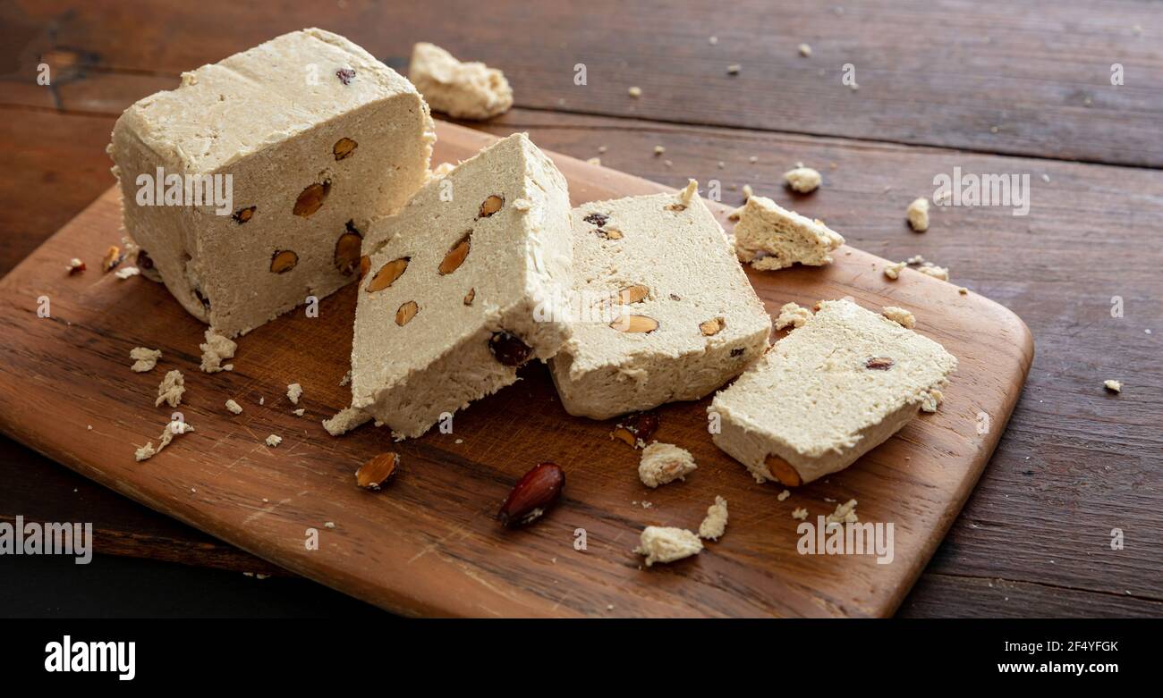 Halva sunflower and almonds on wooden table background. Vanilla halvah ...