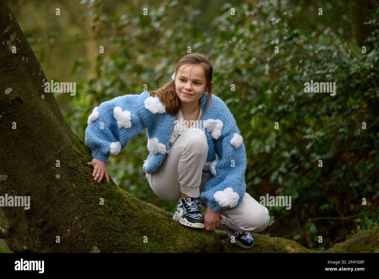Young Girl crouching on a Tree Trunk Stock Photo - Alamy