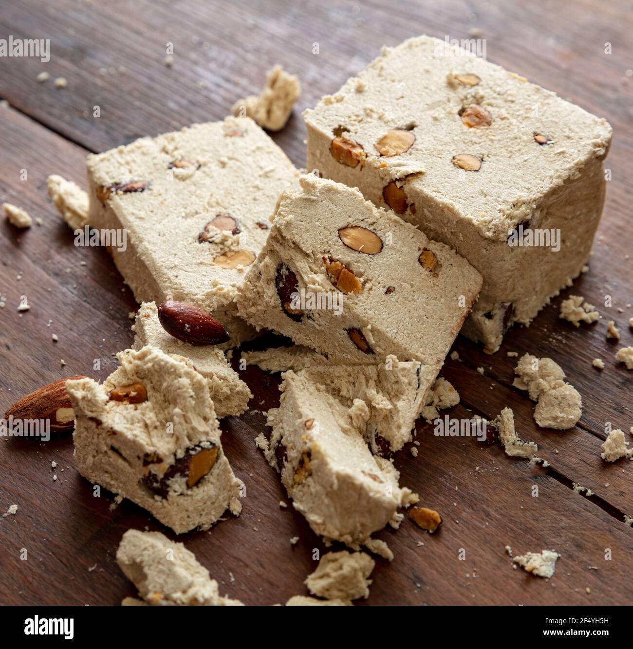 Halva sunflower and almond nuts on wooden table background. Vanilla halvah or halwa crubled ...
