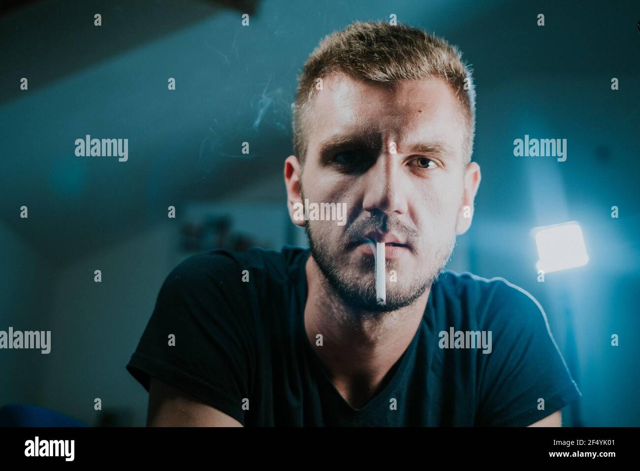 Portrait of a young blonde male smoking a cigarette Stock Photo - Alamy