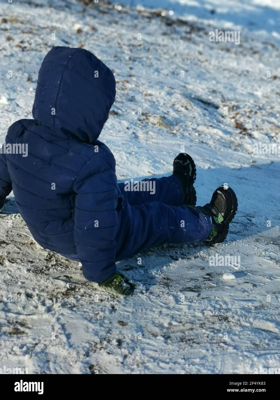 Vertical shot of a child sliding on a slope covered with snow Stock ...