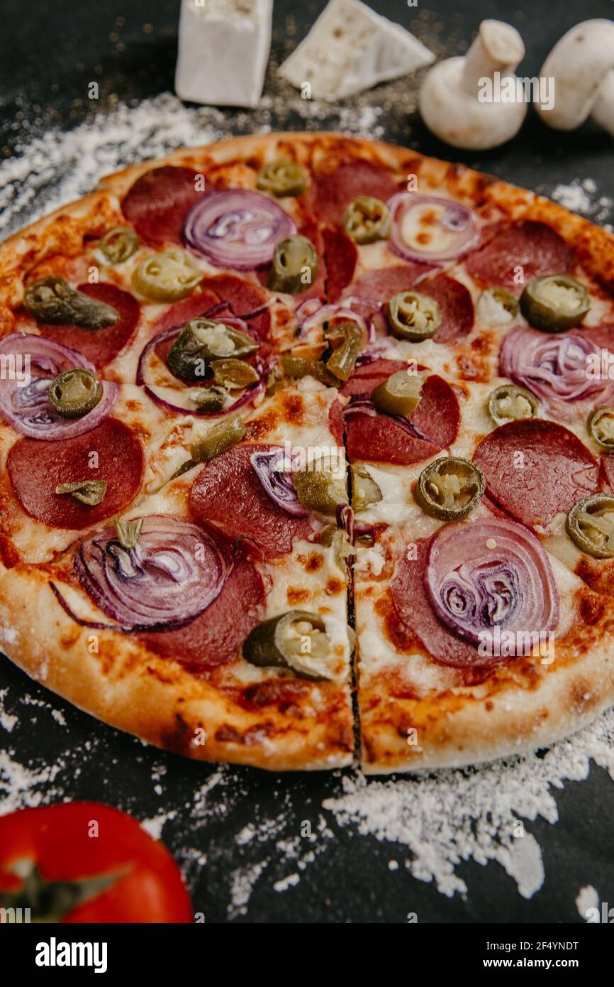 Vertical shot of just made pepperoni with onions and spicy peppers ...