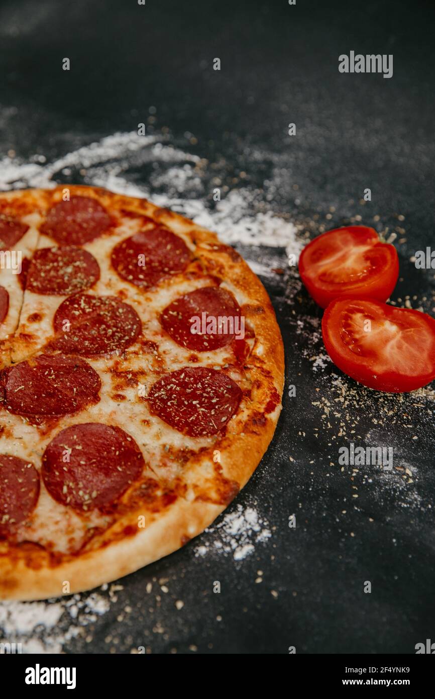 Vertical shot of just made pepperoni with a cut tomato Stock Photo - Alamy