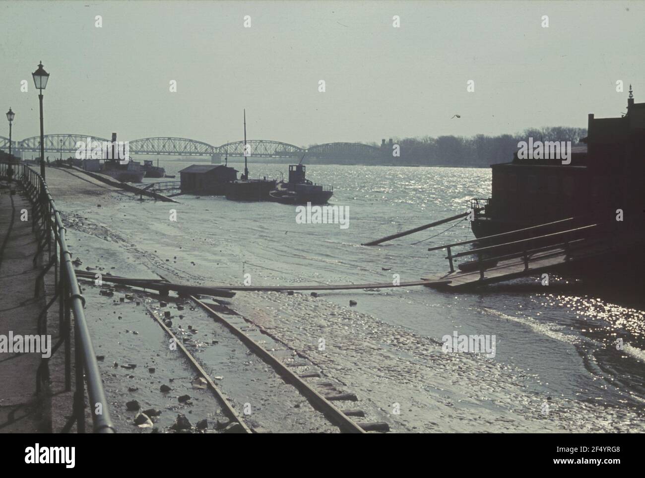 Loading kai at a river shore, well with flood. View to a steel bridge ...
