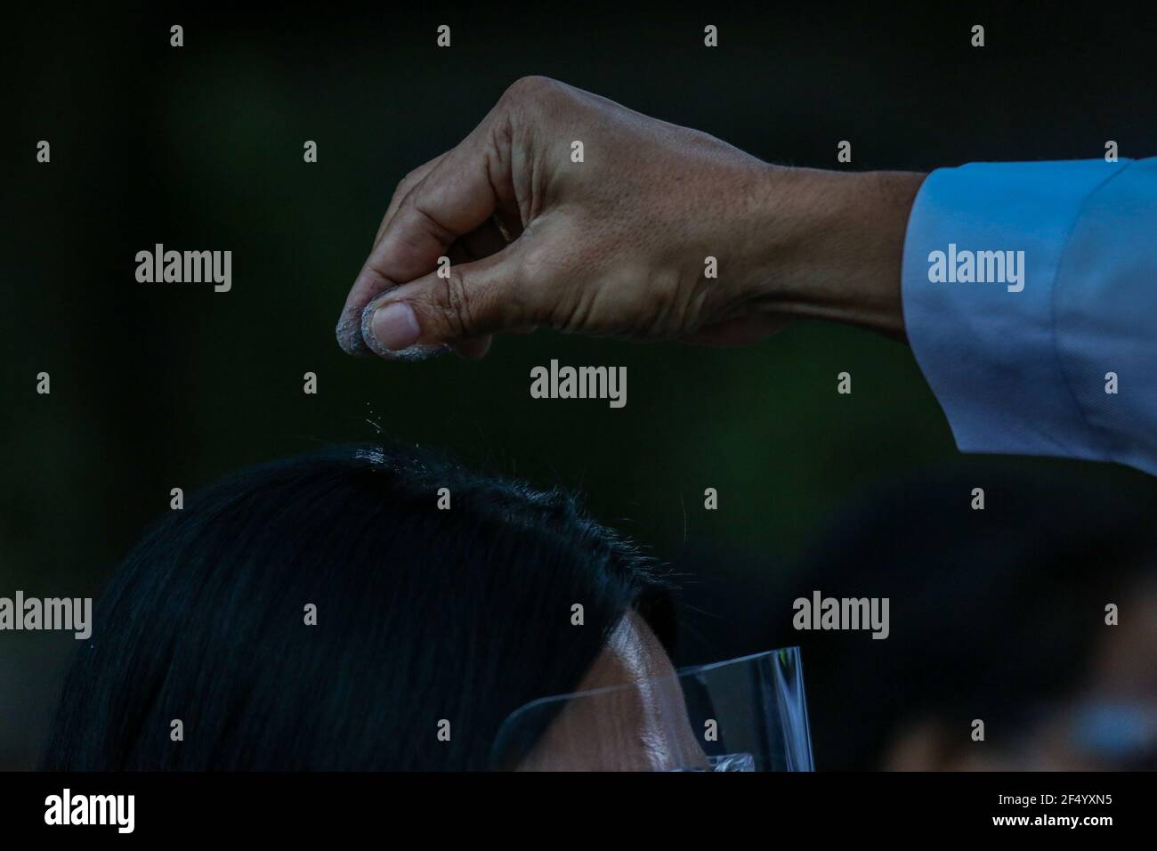 A lay minister sprinkles ash on the head of a Catholic devotee during ...
