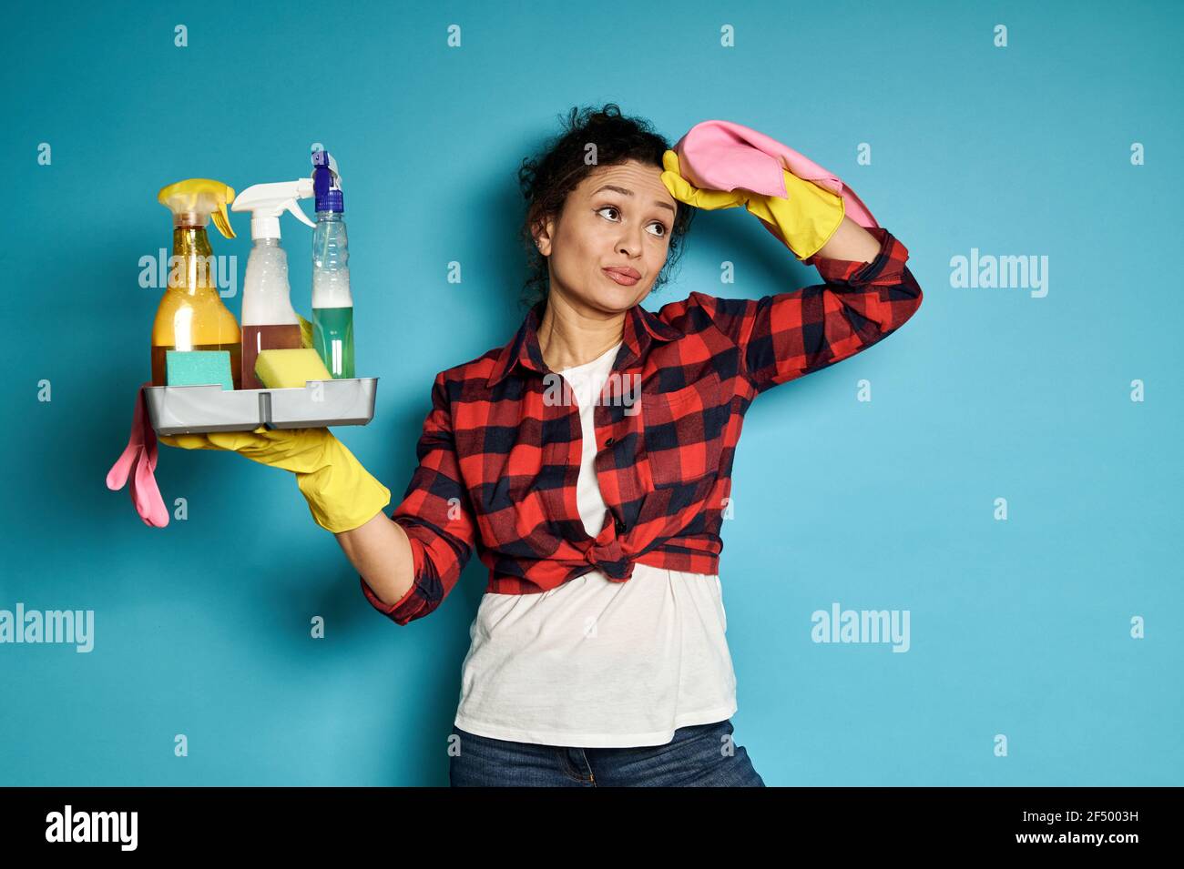 Cute housewife with tray of cleaning tools and products exhausted after ...