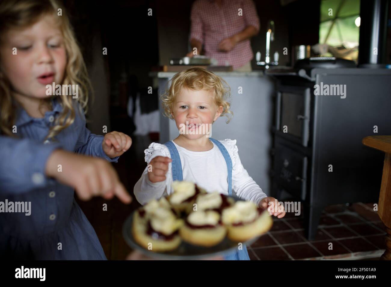 Cute girls reaching for biscuits with jelly and cream Stock Photo - Alamy