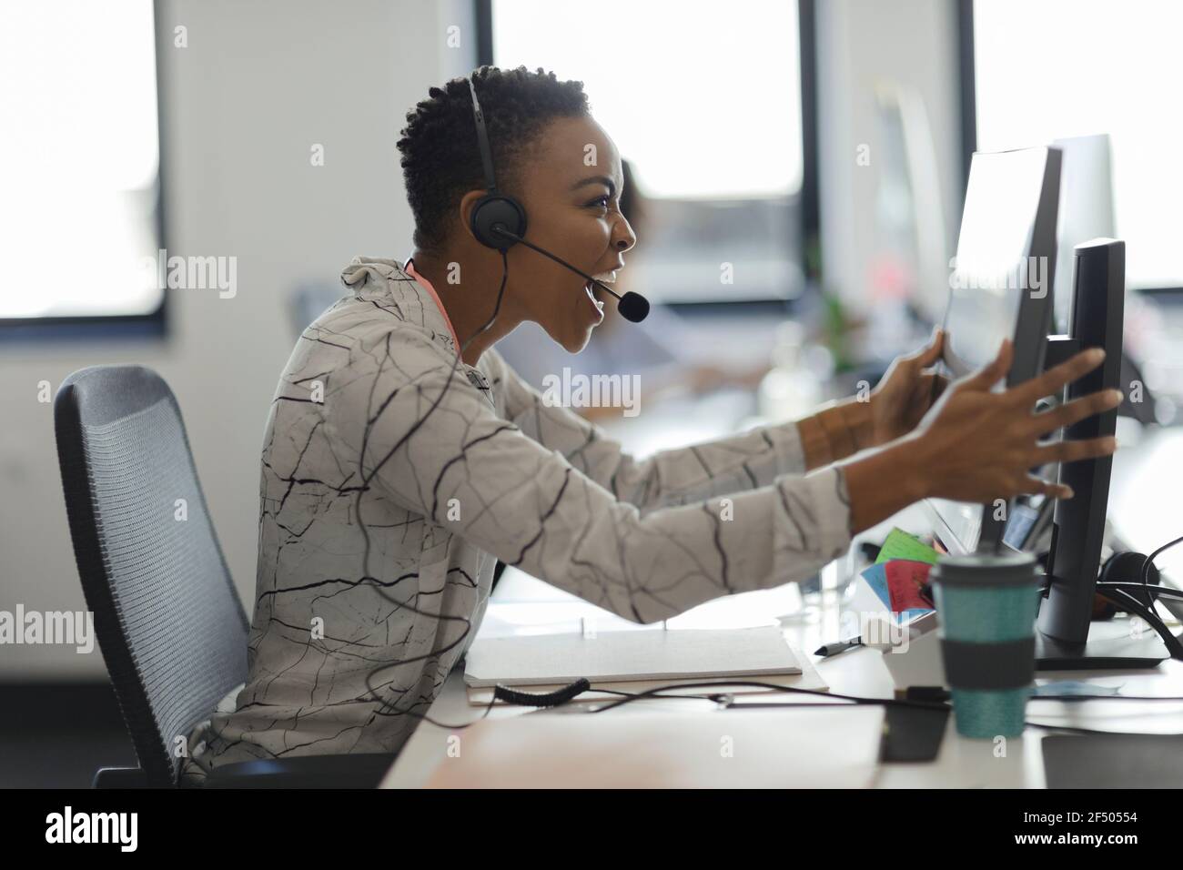 Frustrated businesswoman shaking computer monitor at office desk Stock ...