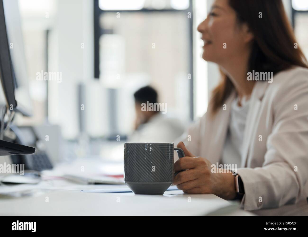 Businesswoman drinking coffee at computer in office Stock Photo - Alamy