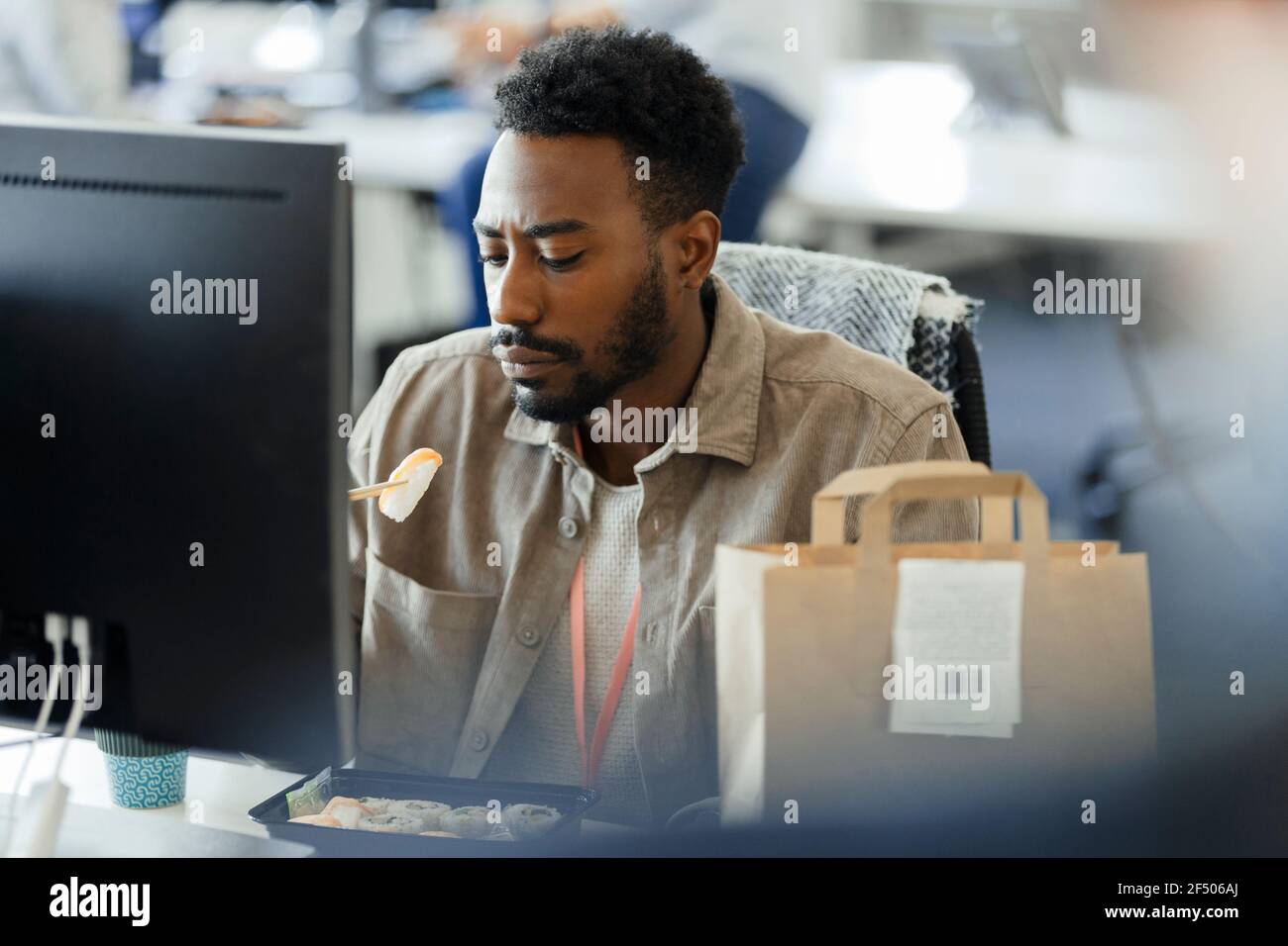 Businessman eating takeout sushi lunch at office desk Stock Photo - Alamy