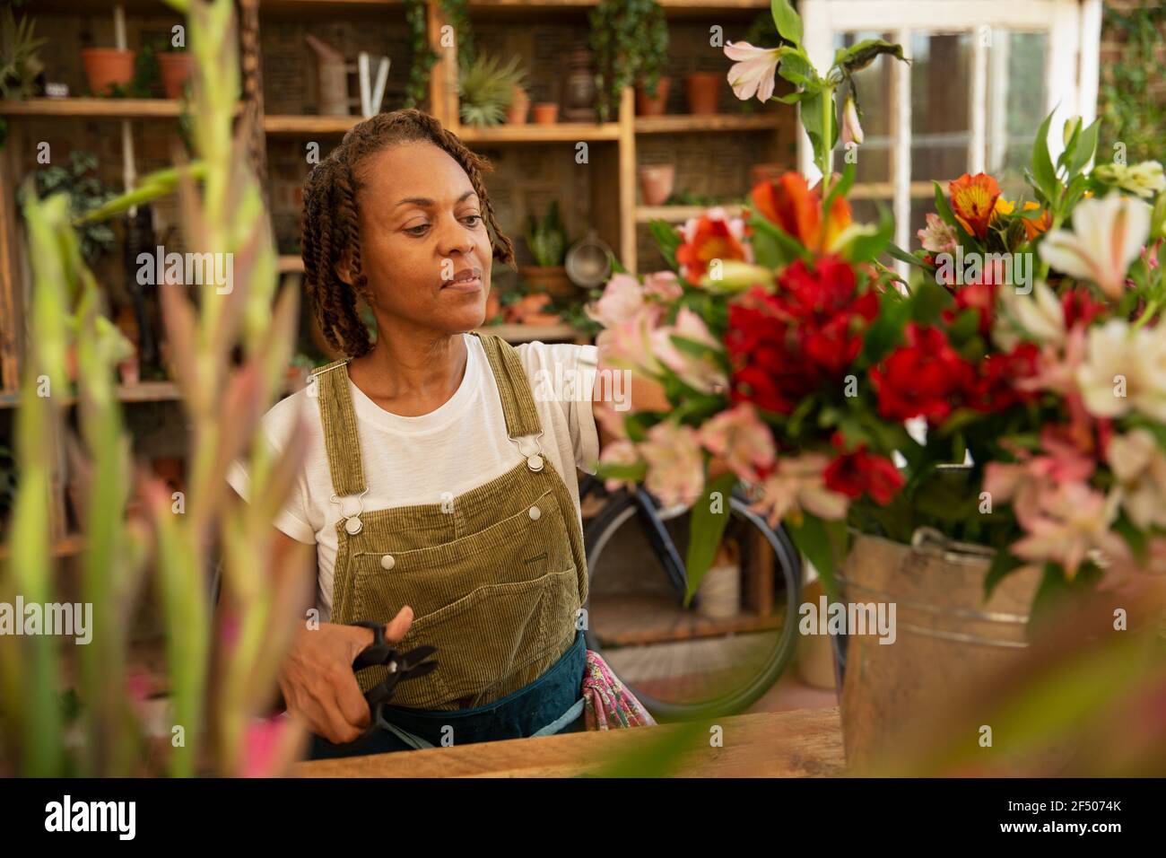 Female florist arranging flowers in shop Stock Photo - Alamy