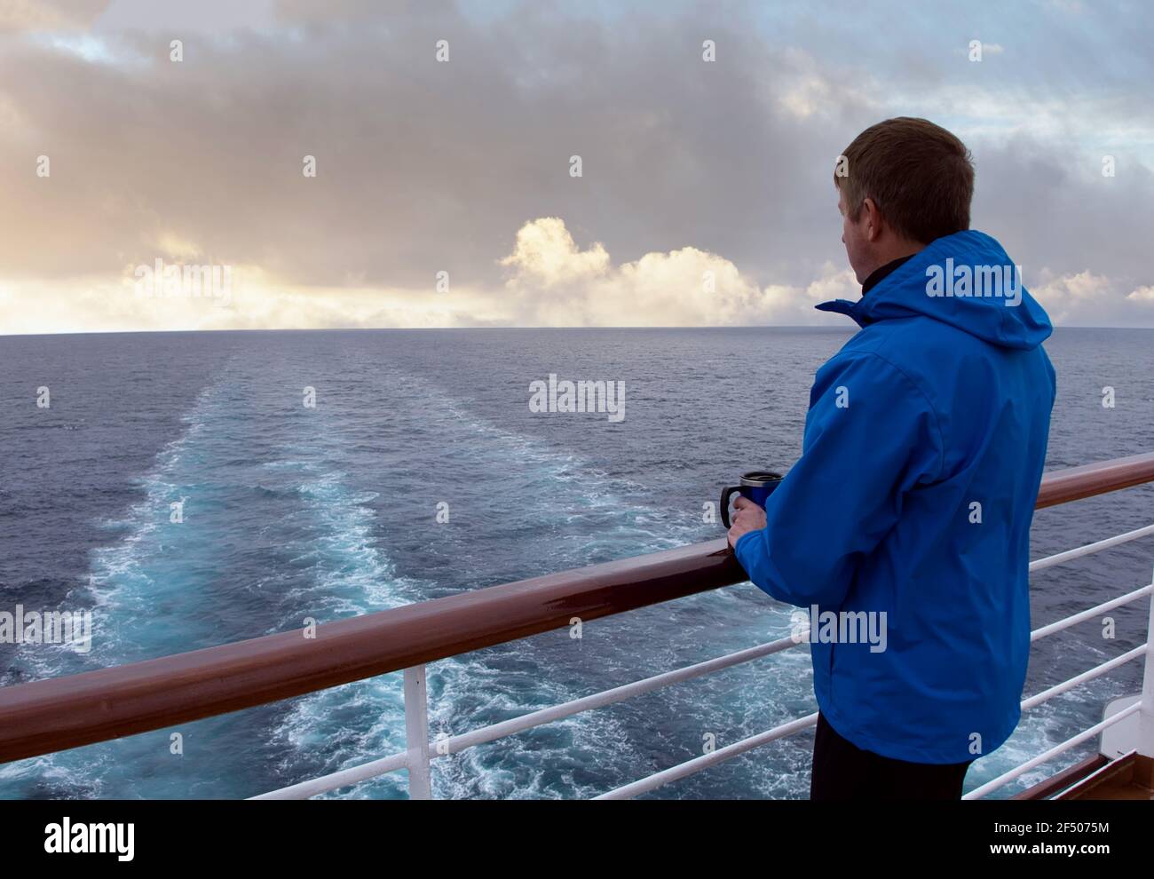Mature man wearing rain jacket while looking from stern of boat out ...