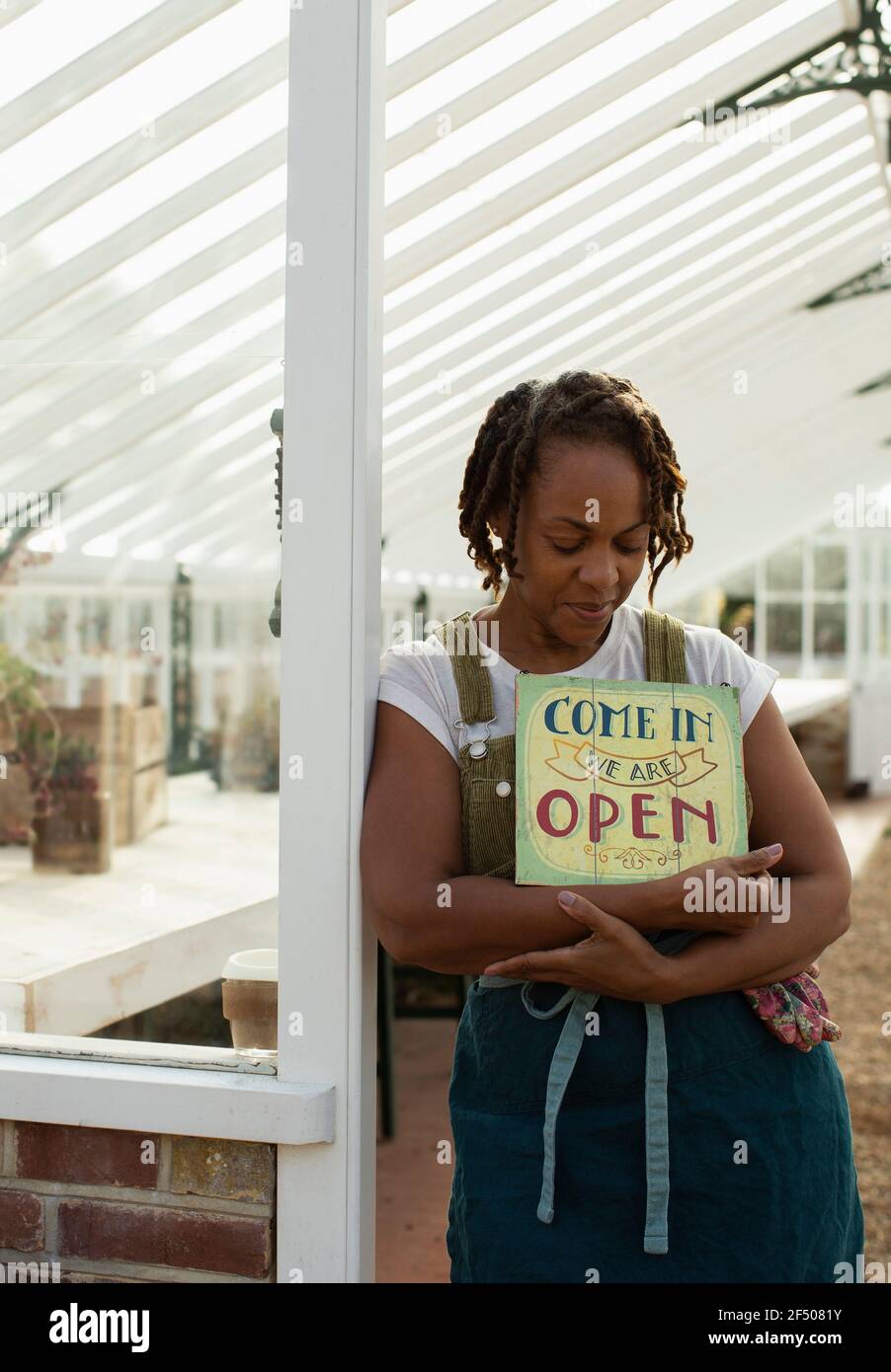 Female plant nursery owner with open sign in greenhouse doorway Stock ...