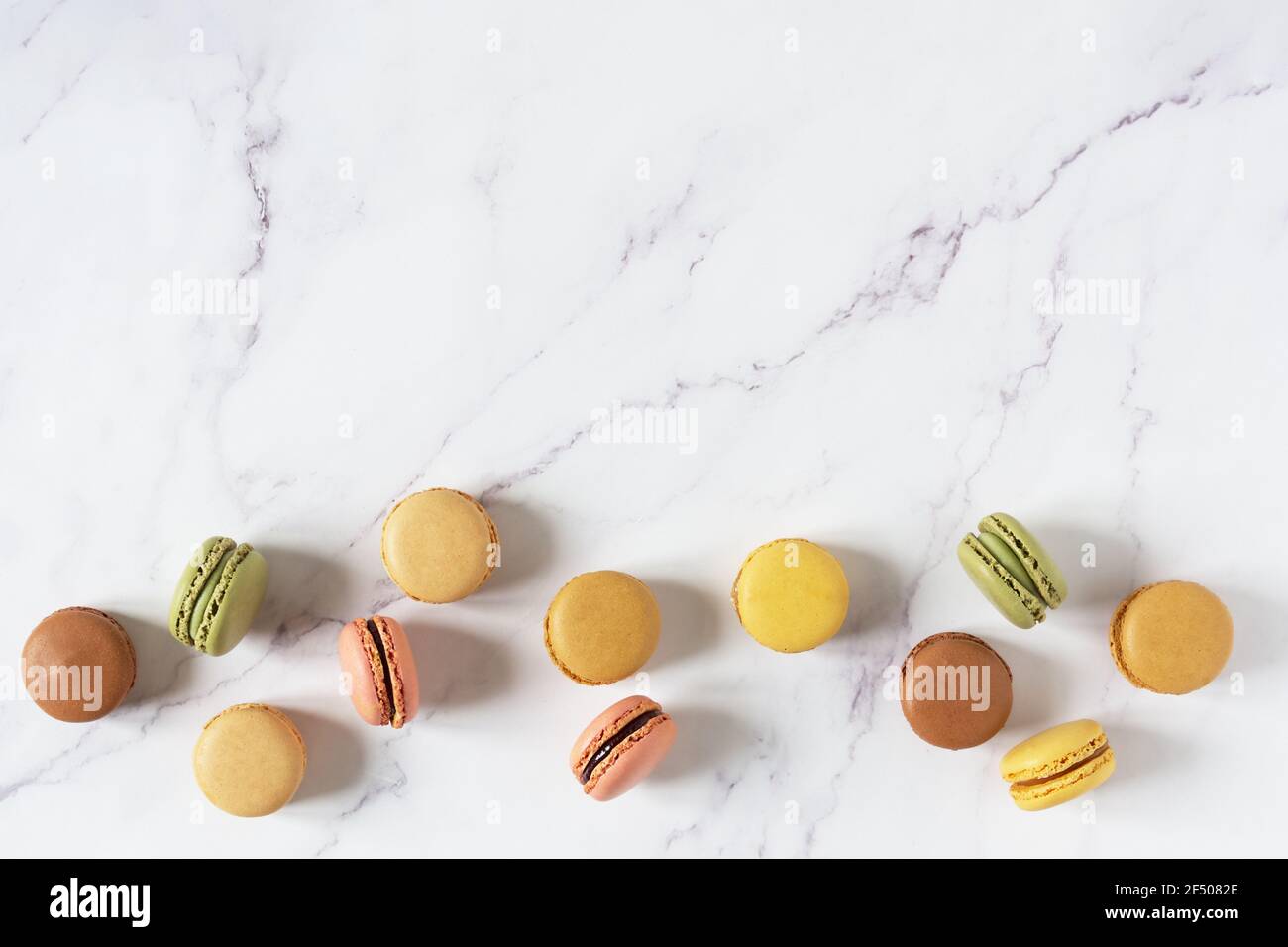 Multi colored french macaroons top view on white marble table. French ...