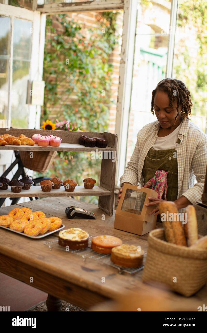 Female baker boxing pastries in shop Stock Photo - Alamy