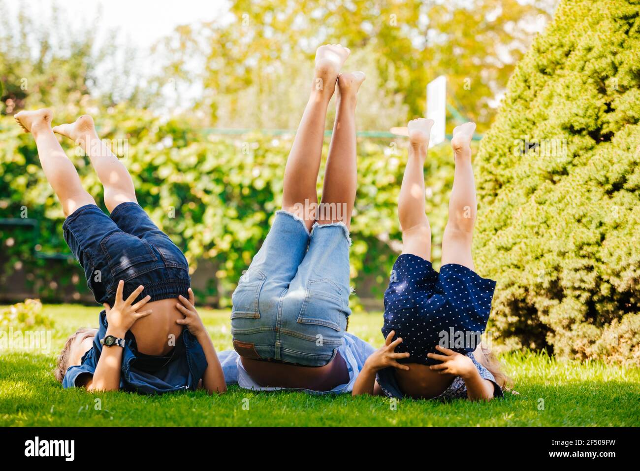 Three little children lying on a green grass Stock Photo - Alamy