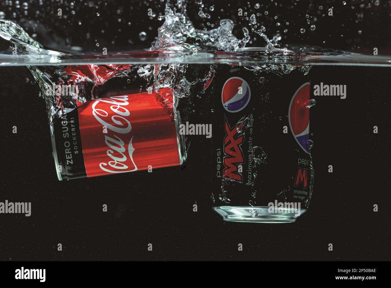 Close up view of two cans falling in water. Coca cola vs Pepsi cola ...