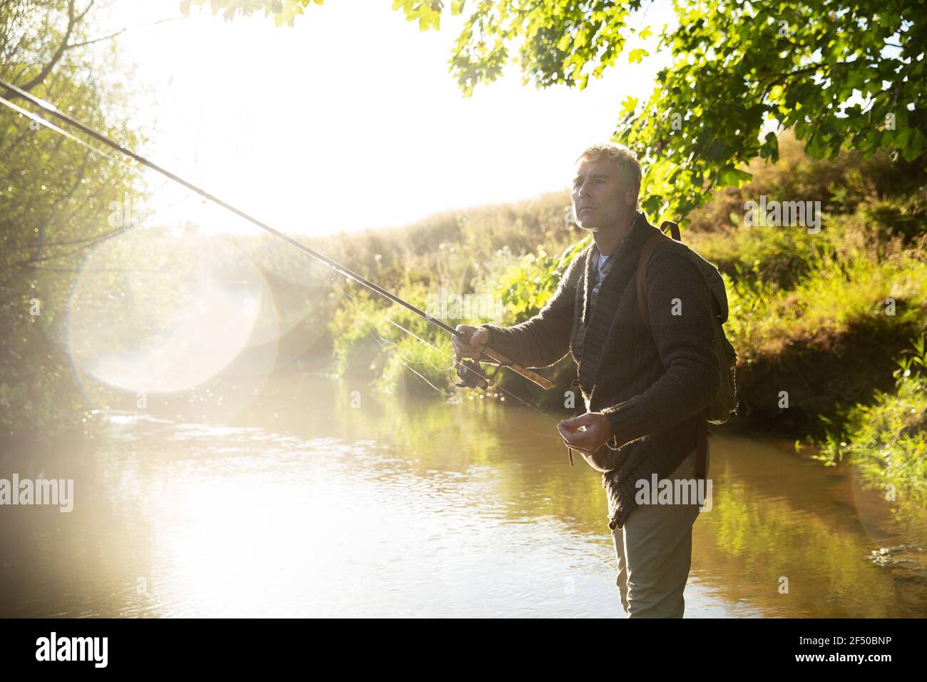 Man fly fishing at sunny idyllic river Stock Photo - Alamy