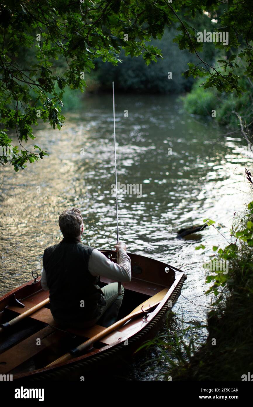 Man fly fishing from boat on river Stock Photo - Alamy