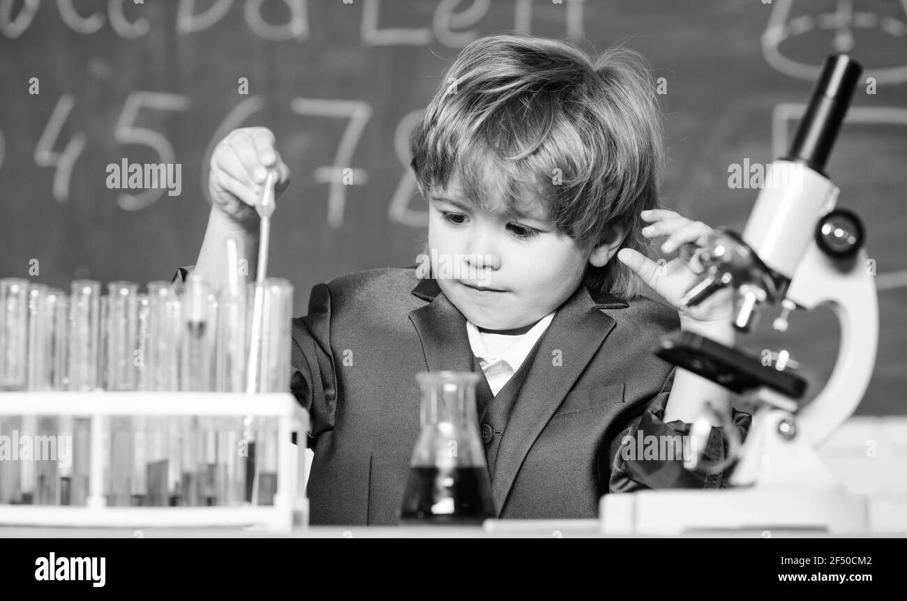 small boy using microscope at lesson. testing tubes with liquid for ...