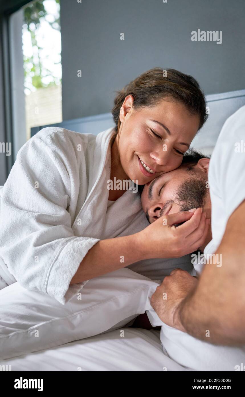 Happy affectionate couple cuddling on bed Stock Photo - Alamy