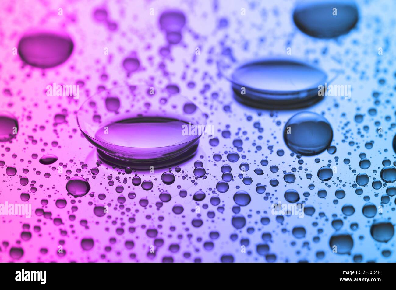 Contact lenses, on pink-blue-green background. Two contact lenses with ...