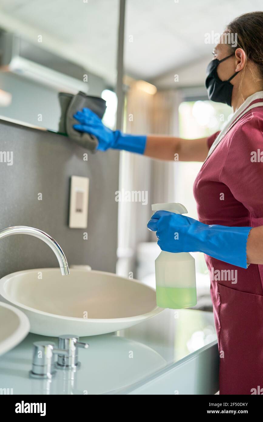 Female hotel maid in face mask and gloves cleaning bathroom Stock Photo ...