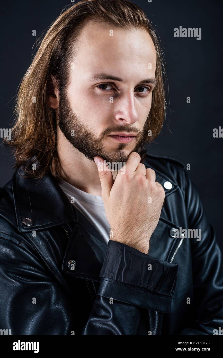 bearded man biker in leather jacket with long hair, beard care Stock ...