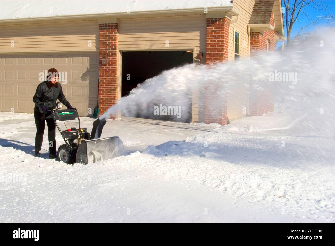 Adult clearing snow from sidewalk and walkway with a snowblower Stock ...
