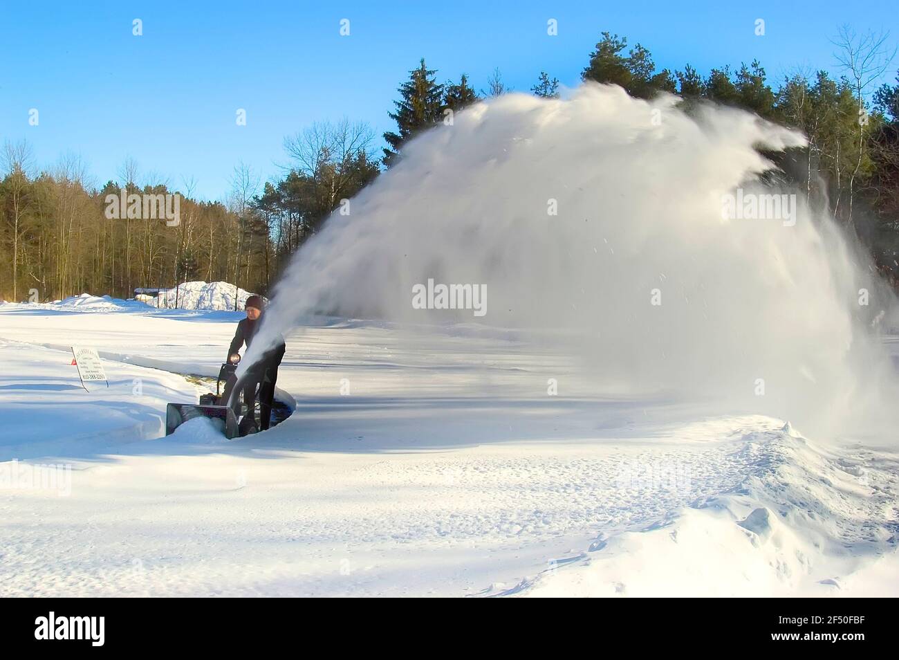 Adult clearing snow from sidewalk and walkway with a snowblower Stock ...