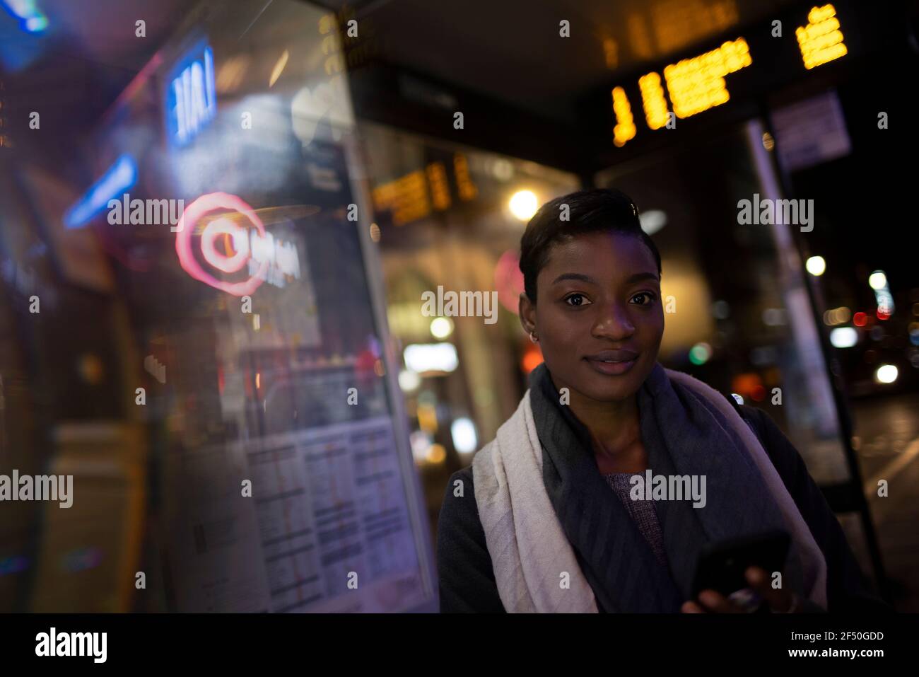 Portrait confident young woman at urban bus stop at night Stock Photo ...