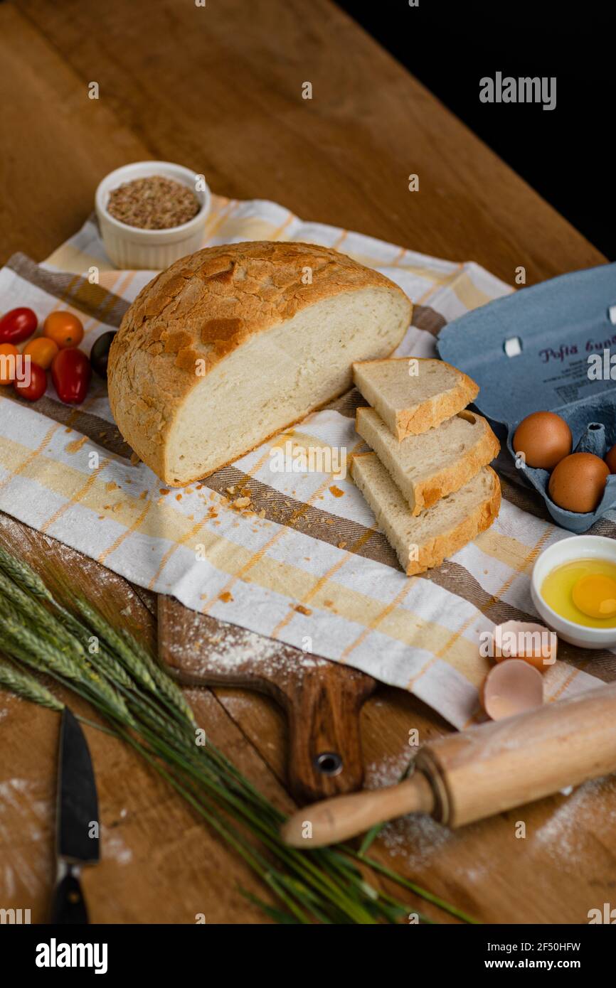 Gold rustic crusty loaves of bread on a tablecloth with tomatoes and ...