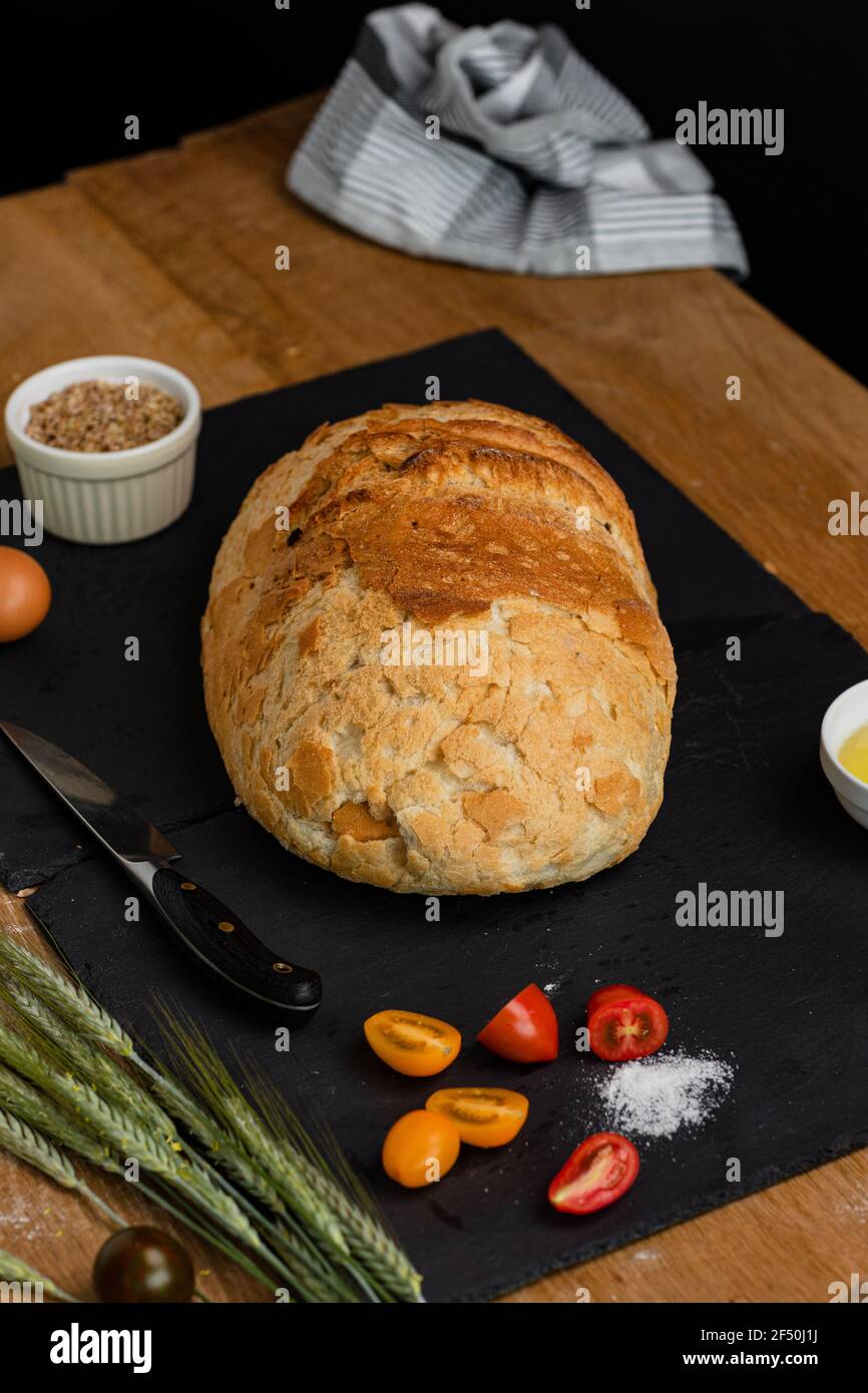 Gold rustic crusty bread on a blackstone board with tomatoes and other ...