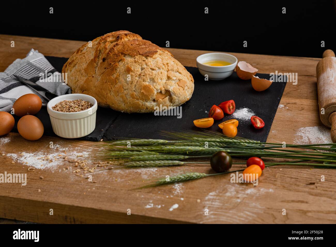 Gold rustic crusty bread on a blackstone board with tomatoes and other ...