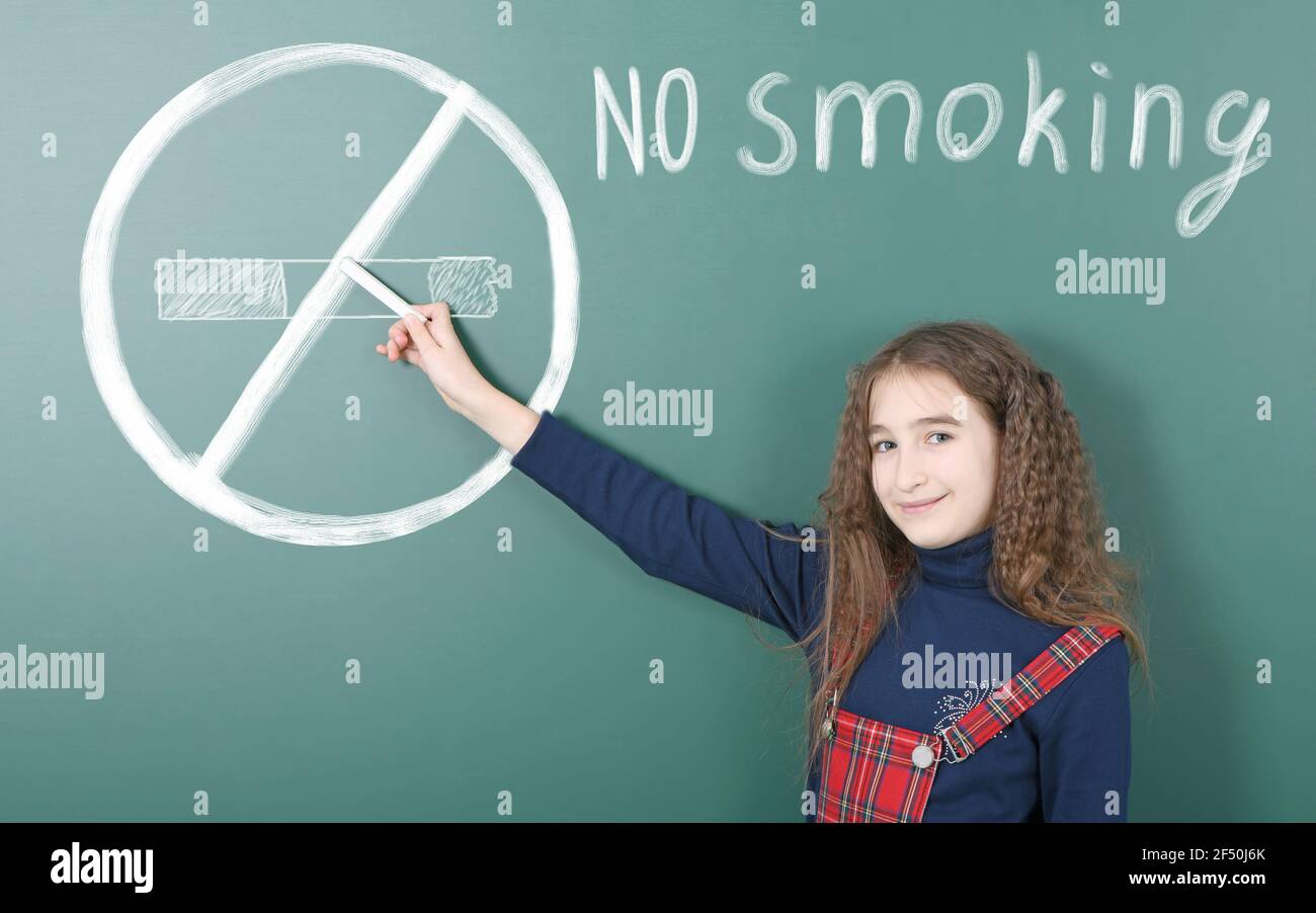Pre-adolescent girl points finger at drawn chalk crossed out cigarette ...