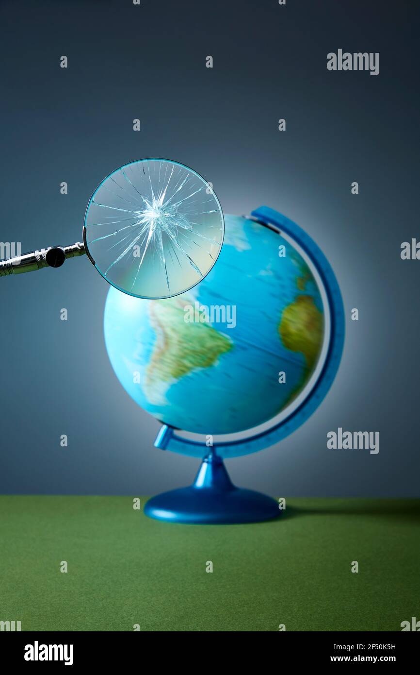 Broken magnifying glass over spinning globe Stock Photo - Alamy