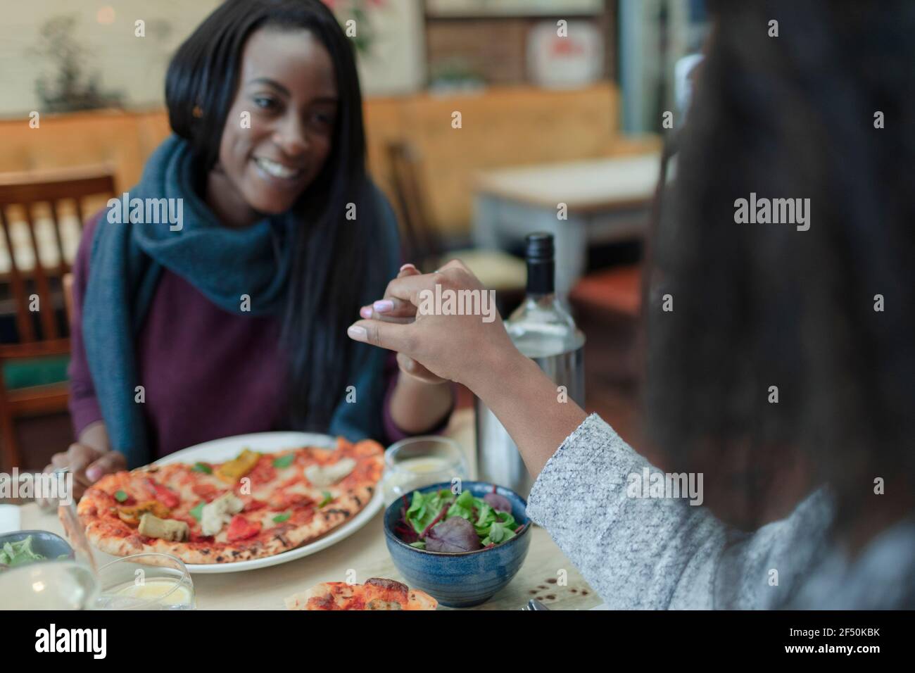 Mother and daughter holding hands over lunch in restaurant Stock Photo ...