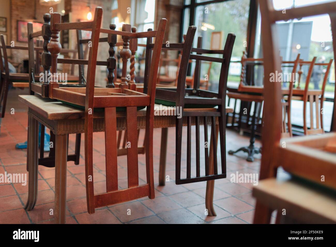 Wooden chairs upside down on tables in empty restaurant Stock Photo - Alamy