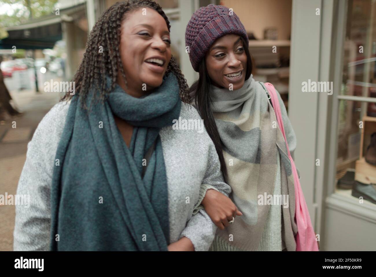 Happy mother and daughter walking arm in arm outside storefront Stock ...