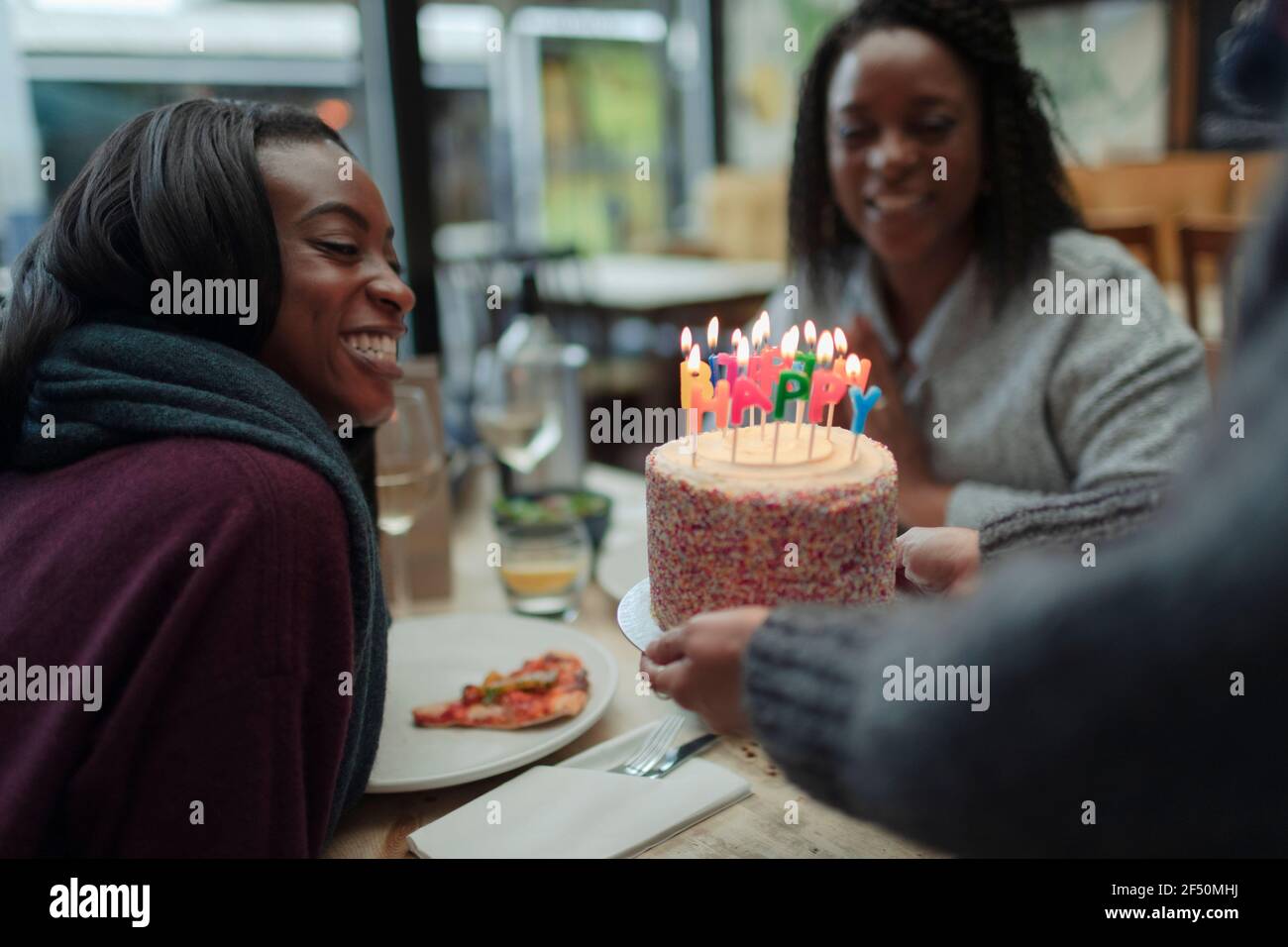 Waitress serving birthday cake to mother and daughter in restaurant ...