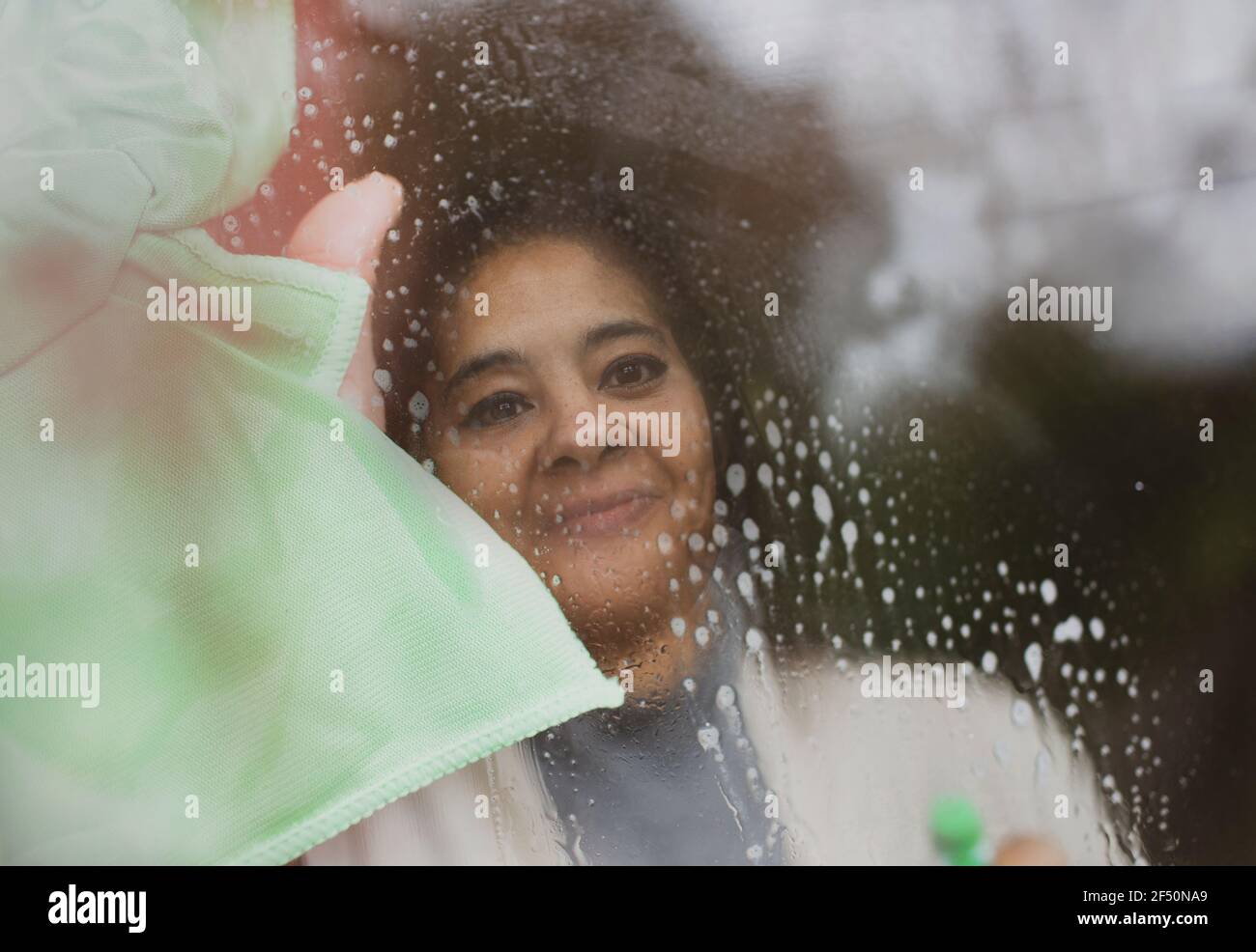 Portrait smiling woman cleaning window with glass cleaner and rag Stock ...