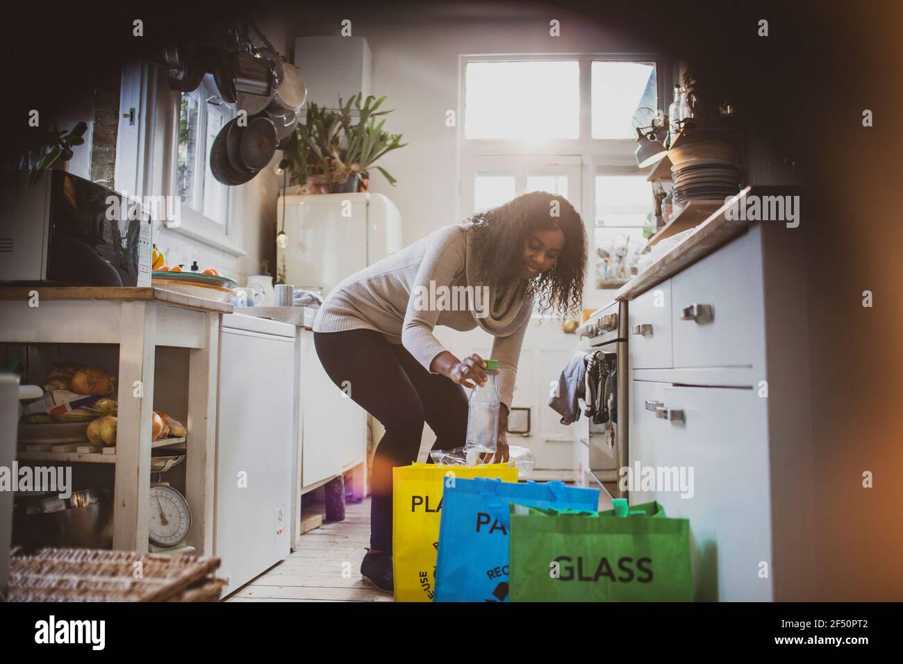 Young woman sorting recycling on kitchen floor Stock Photo - Alamy