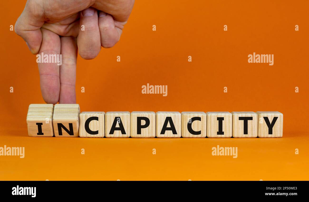 Capacity or incapacity symbol. Businessman turns wooden cubes and ...