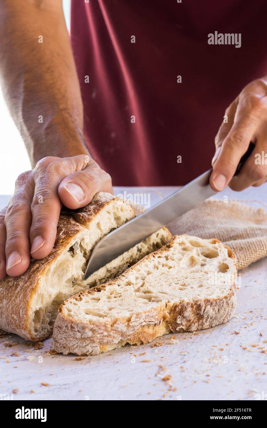 vertical image of man's hands breaking organic bread in the foreground ...